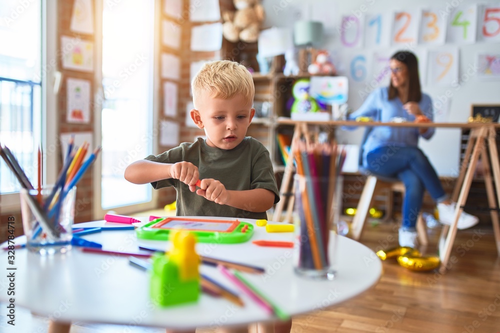 Young caucasian child playing at playschool with teacher. Mother and ...