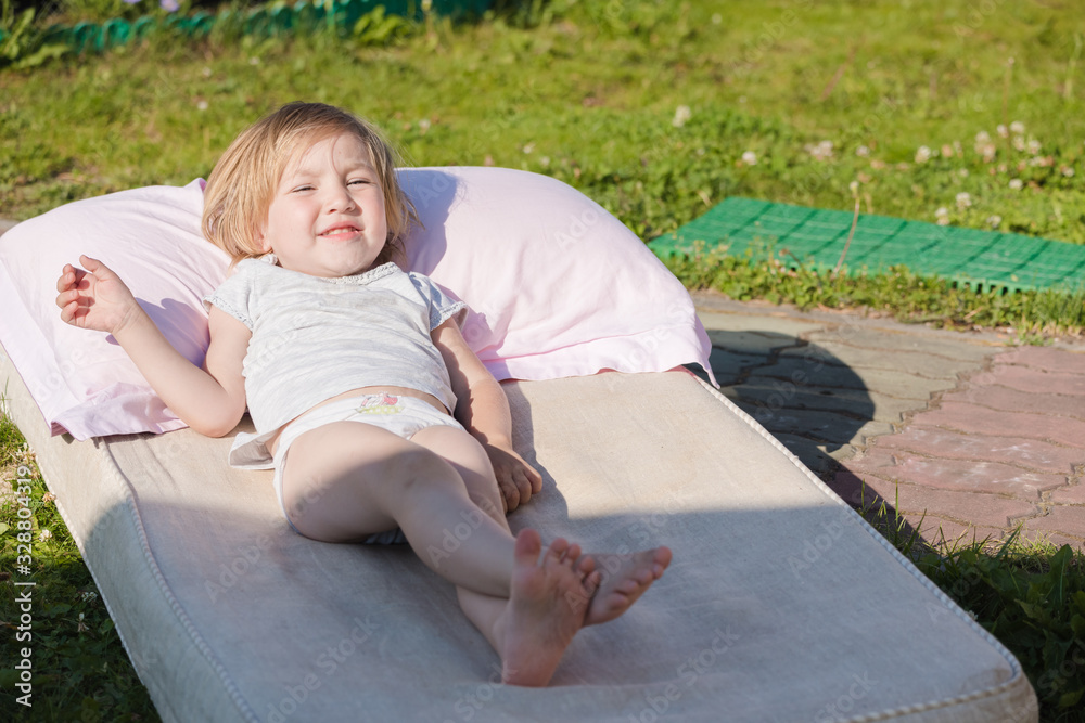 Foto de Small child sunbathes in the sun while lying on mattress in the ...