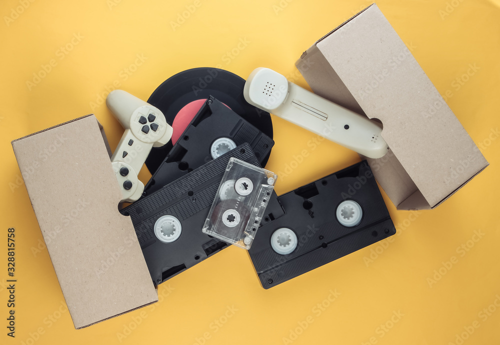 Cardboard box with video cassette, retro film camera, gamepad, vinyl ...