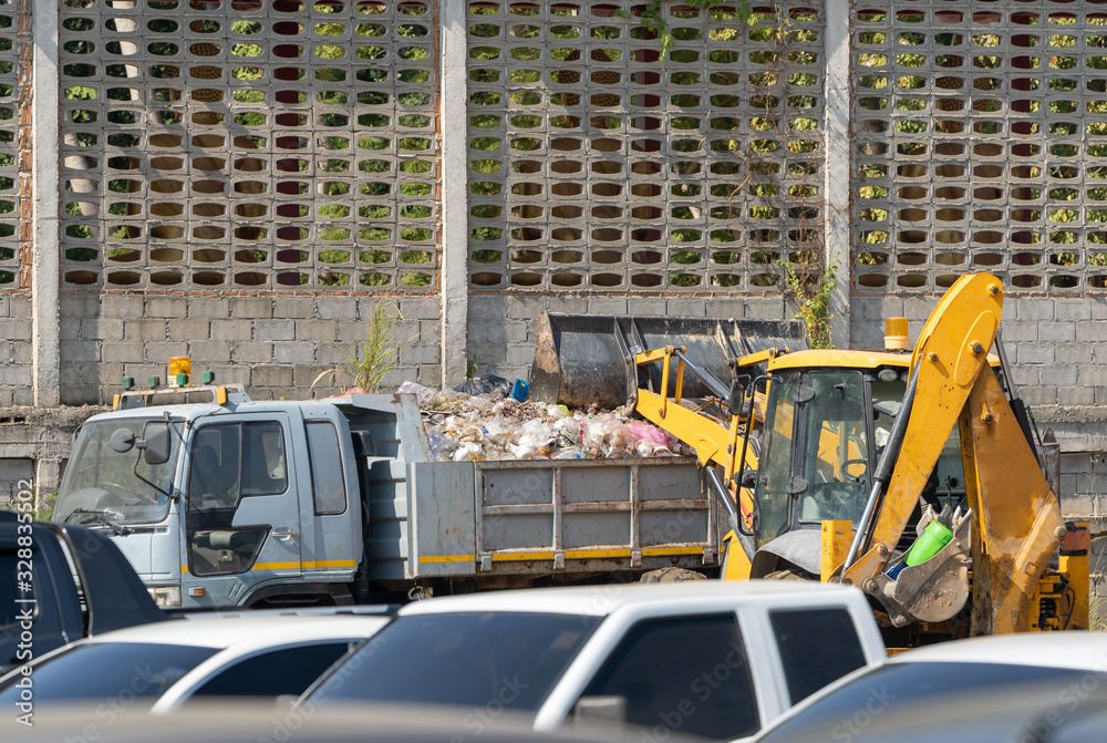 Yellow digger car is raising up polluted waste into garbage truck at ...