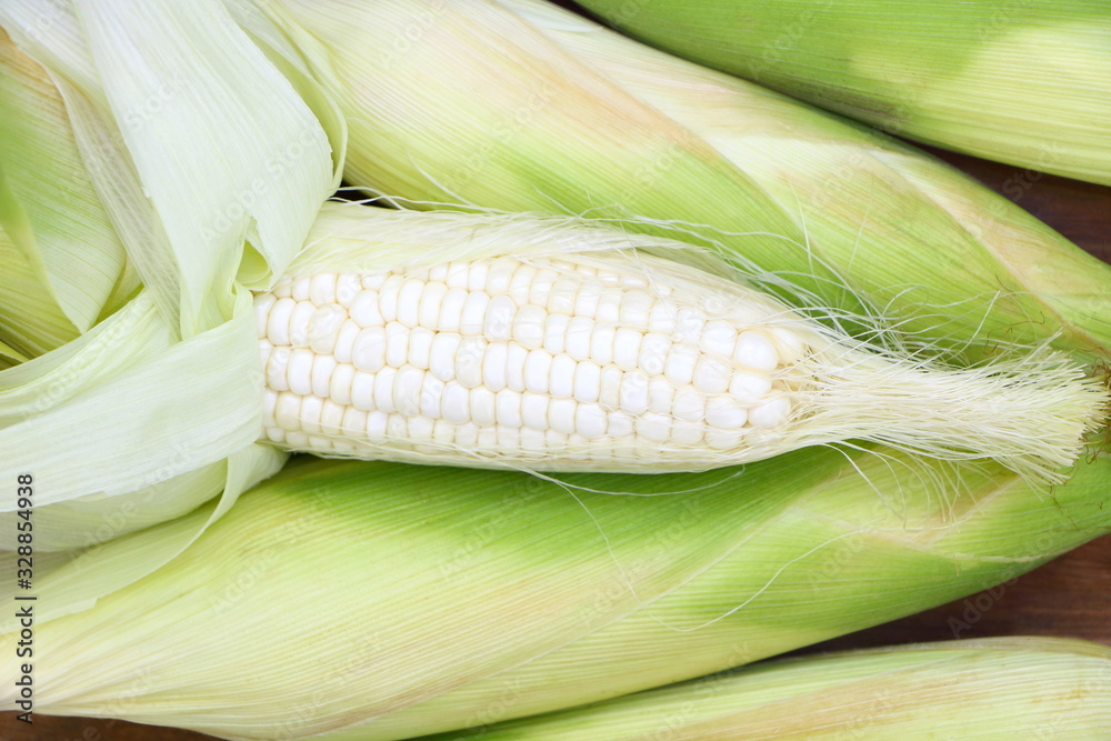 Close up isolated raw white corn (peeled can see inside) on brown wood ...