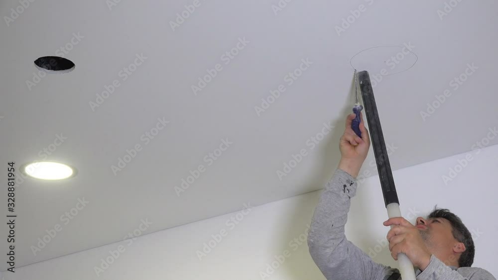 man saw round hole in plasterboard ceiling. Led light panel ...
