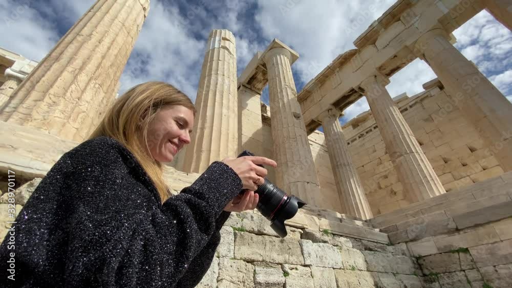 A pretty blonde woman photographer take pictures of columns of ...