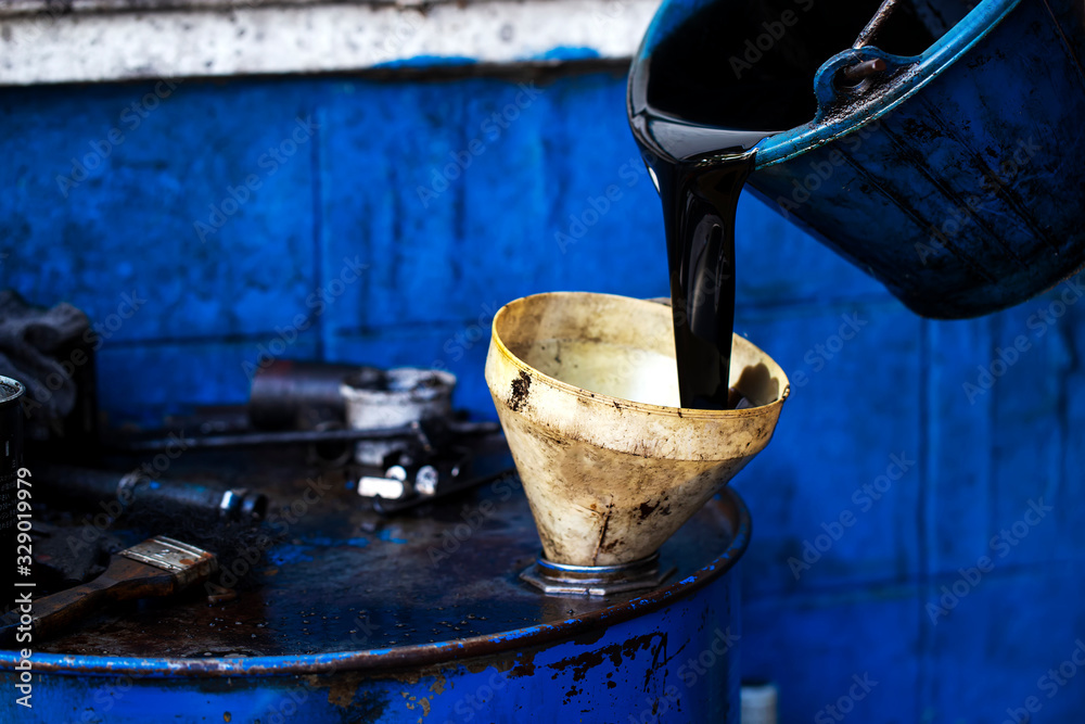 Old oil is drained from the car's engine, dumped into the tank. Stock ...