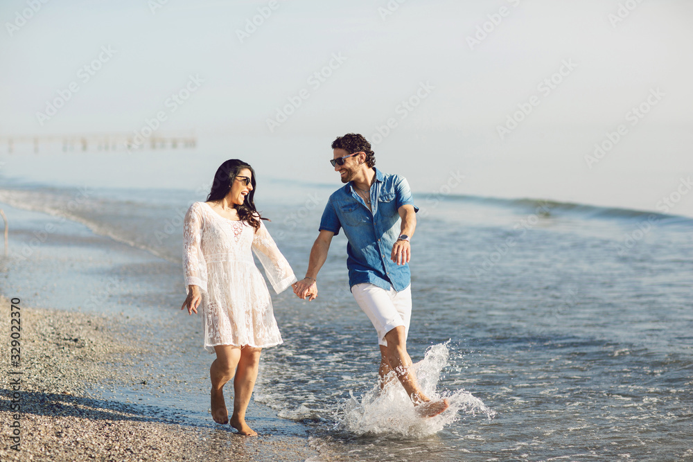 Happy couple walking and playing on the beach, soaking his feet in the ...