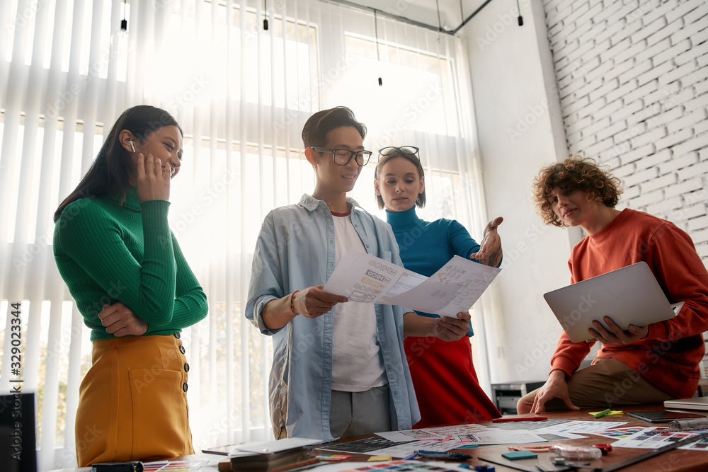 Developing new website. Group of four young designers in casual wear ...