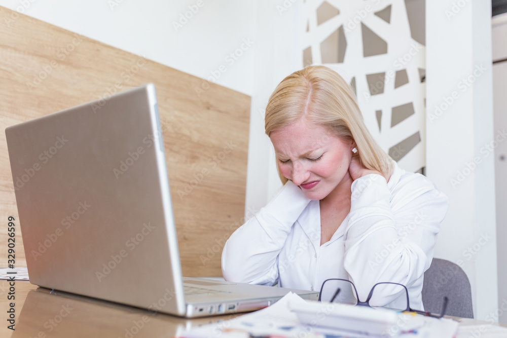 Businesswoman feeling pain in neck after sitting at the table with ...