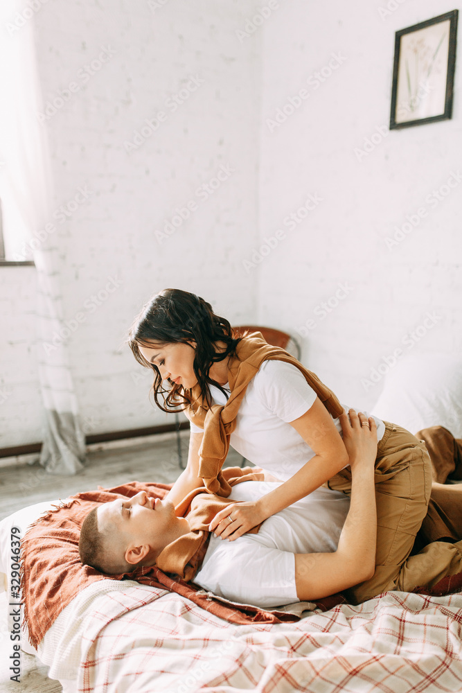 Beautiful couple on the bed. Love story in the interior Studio. Happy and laughing people. At ...