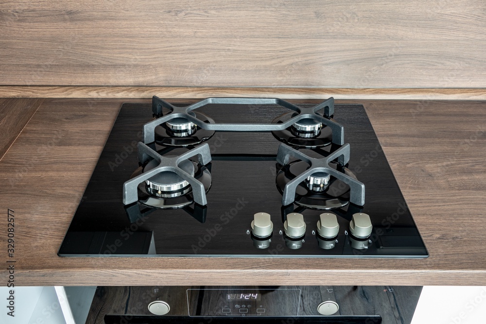 A modern gas cooker with ceramic hob, electric oven and a dark brown ...