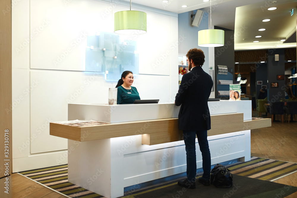serious female receptionist worker standing at hotel counter, close up ...