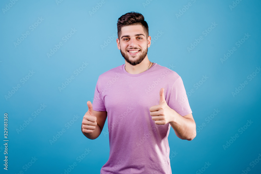 handsome smiling guy showing thumbs up isolated on blue background ...