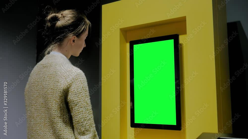 Woman looking at vertical blank digital interactive green display wall ...