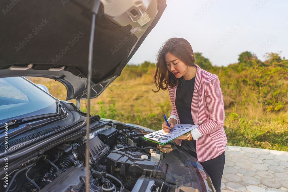 mechanic asian female car inspector holding a pen clipboard checking on ...