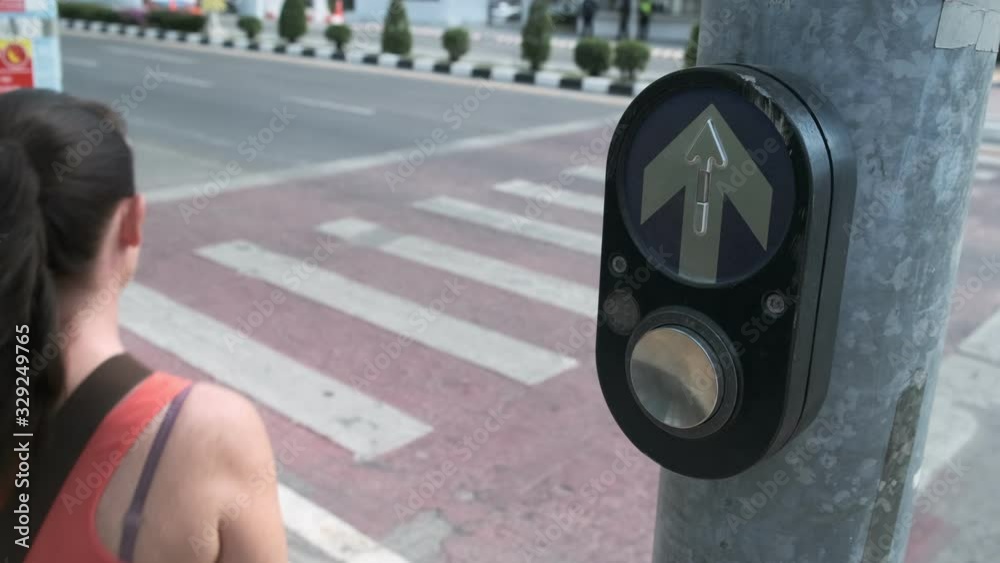 woman pedestrian presses finger on traffic signal switch button at ...