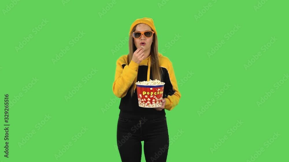 Modern girl in yellow hat in 3D glasses is watching an exciting movie ...