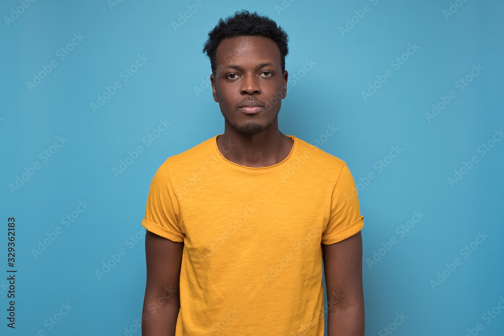 Portrait of serious African American man in yellow shirt with no ...