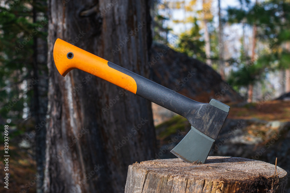 Foto de Tourist ax on a stump in a summer forest. Chopping wood with an ...