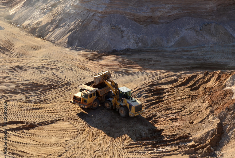 Wheel loader loads sand into heavy mining dump truck at the opencast ...