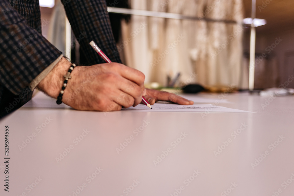 Hands drawing a black ink clothing design sketch, view over the ...