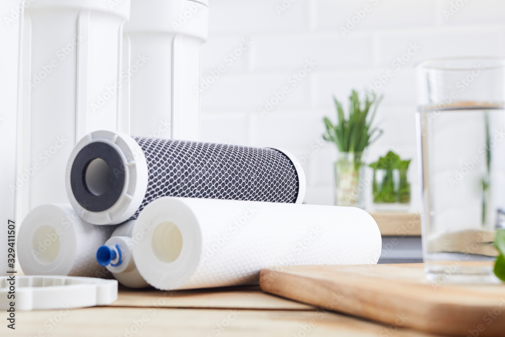clean water with osmosis filter and green leaves on wooden table in a ...
