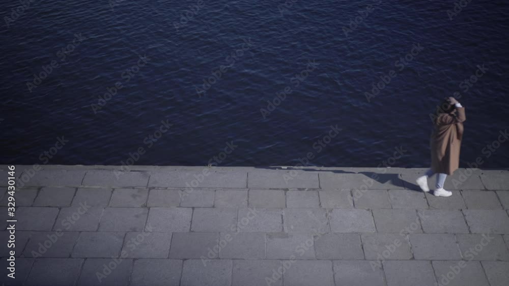 Top view of young Caucasian girl walking along river embarkment from ...