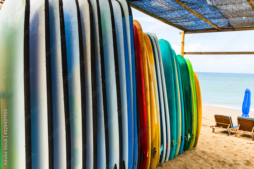 Surfboards of different color and size are standing on the beach in ...