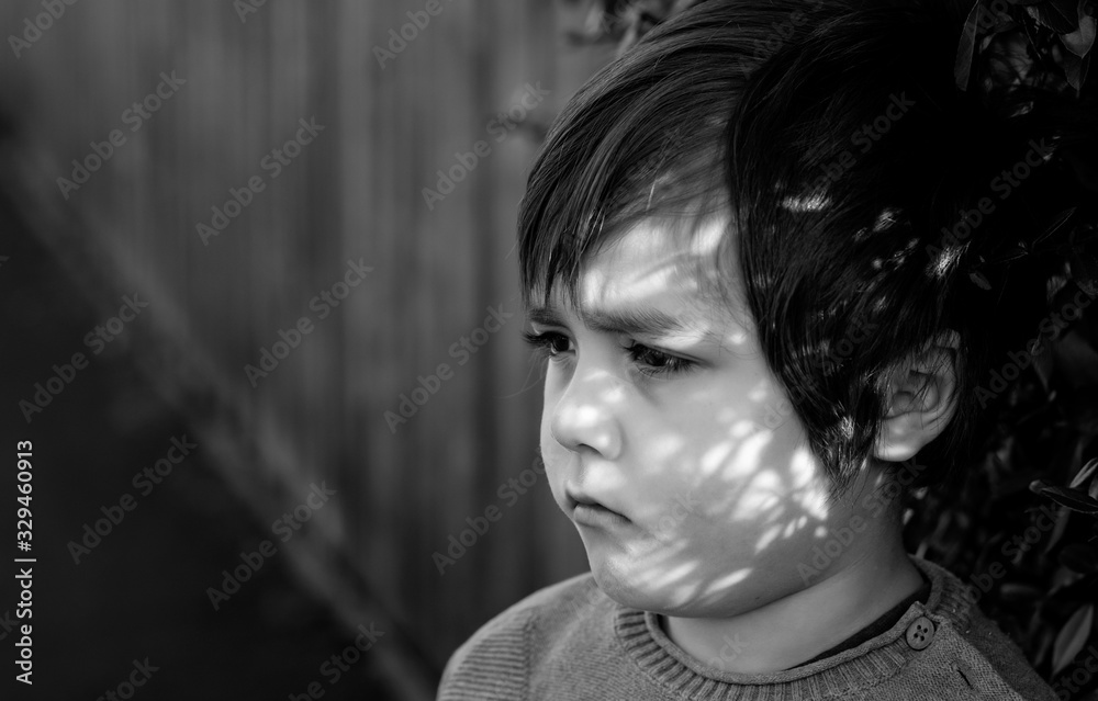 Emotional portrait of Unhappy boy standing next to wooden wall with sad ...