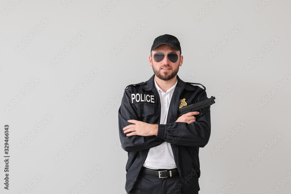 Male police officer with gun on light background Stock Photo | Adobe Stock