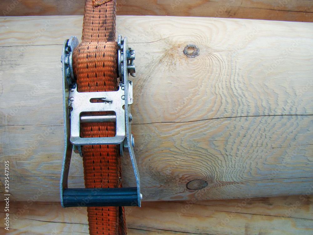 Fastening belt with tensioner. Peeled logs in a horizontal position ...