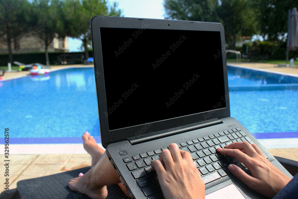 Screen mockup of laptop used by young woman laying near swimming pool ...