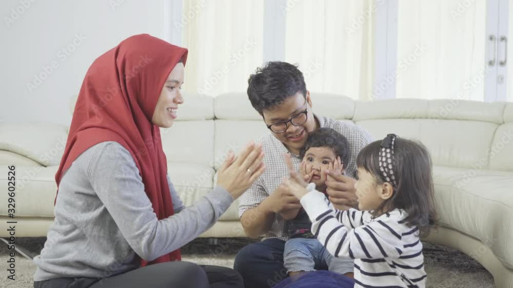 Happy muslim family playing together while sitting in the living room ...