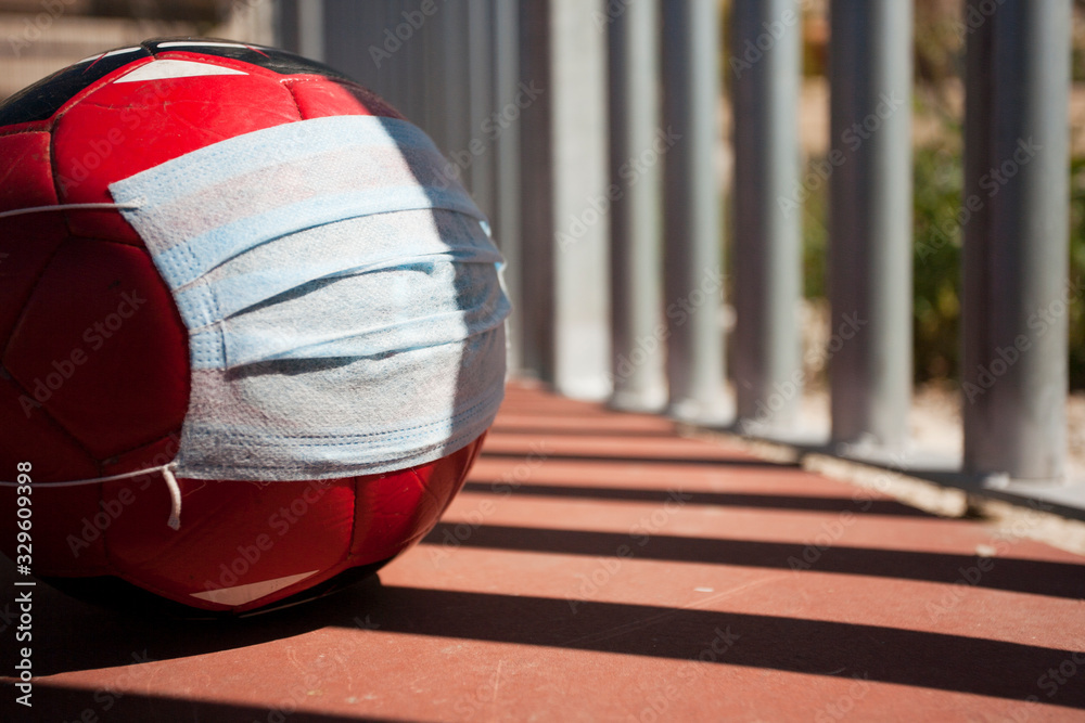 coronavirus concept in sport, soccer ball with breathing mask, closed ...