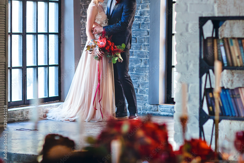 The bride in wedding dress and groom are hugging near the window. Photo ...