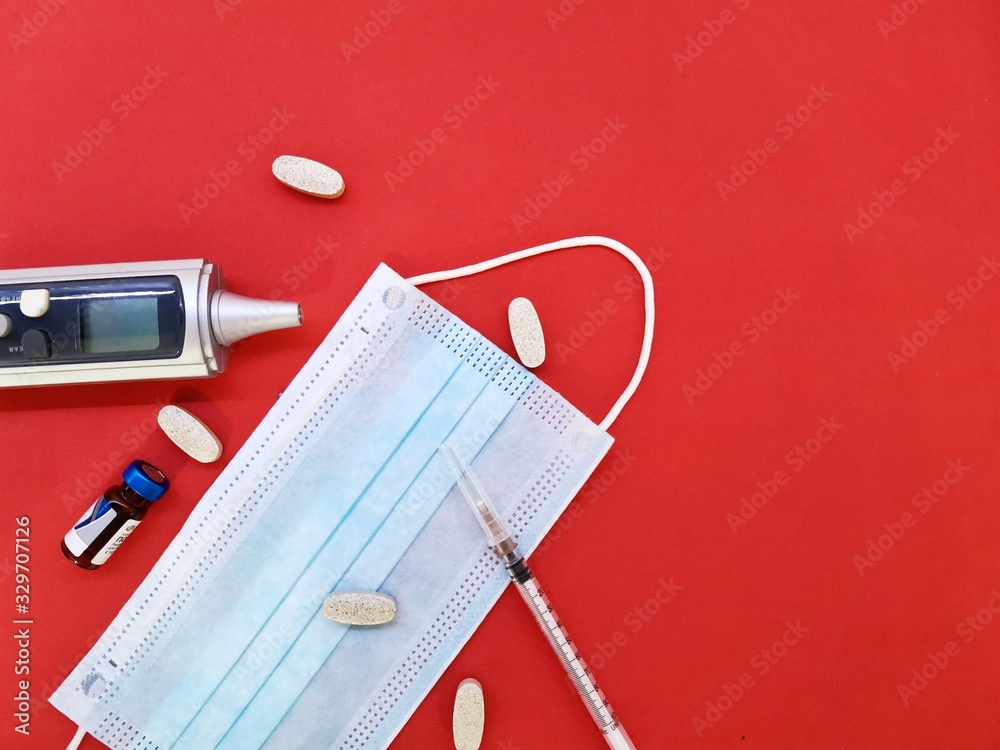 Medical mask, thermometer, tablets, syringes, on a red uniform ...
