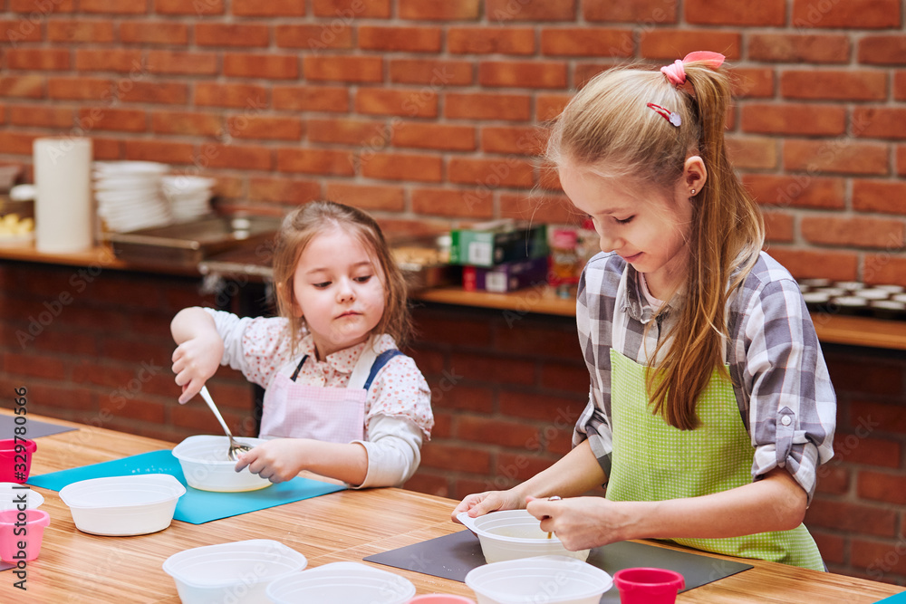 Little girls stirring the yolk with sugar. Kids taking part in baking ...