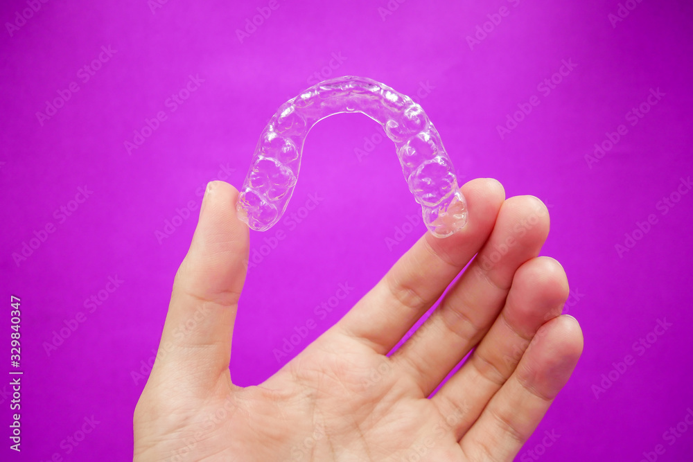 hand holding clear plastic retainer teeth that isolated on purple ...