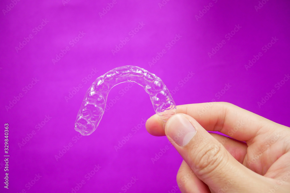 hand holding clear plastic retainer teeth that isolated on purple ...