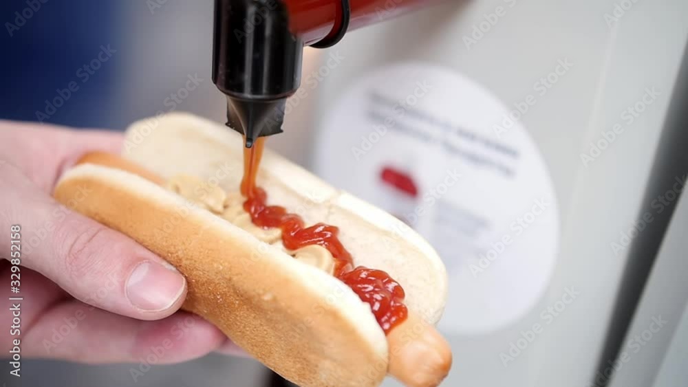 Ketchup pouring a hot dog with sausage from a vending machine in a fast ...