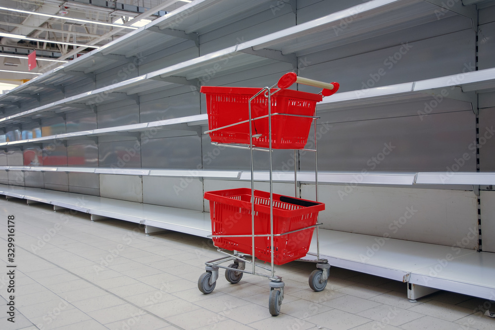 shopping trolley with empty baskets against empty shelves in grocery ...