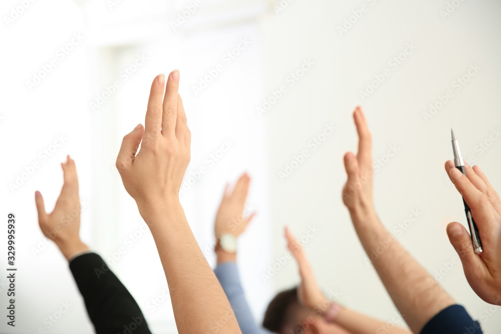 People raising hands to ask questions at business training on light ...