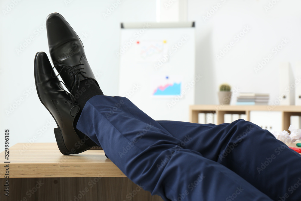 Lazy office employee resting with feet up on desk at workplace, closeup ...