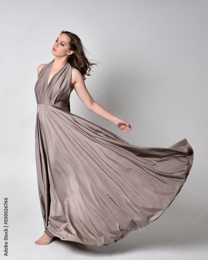 Portrait of a pretty brunette girl wearing a long silver evening gown ...