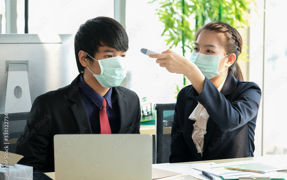 Women in the office use thermoscan to check temperature of the man who ...