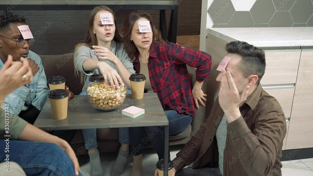 Diverse group of friends playing Who am I game with sticky papers ...