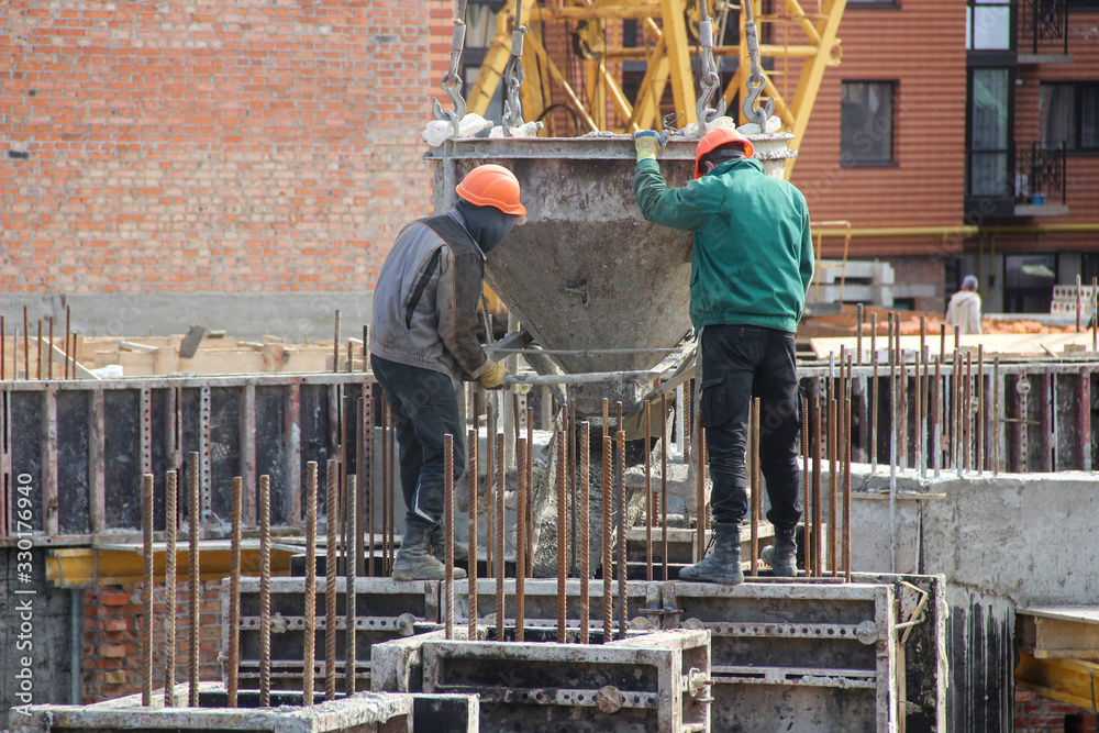 Workers at construction site casting a concrete mixture into the form ...
