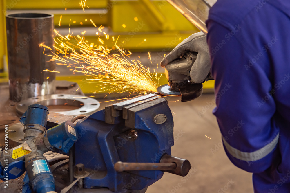 workers cutting metal sheets with electric grinder in the workshop ...
