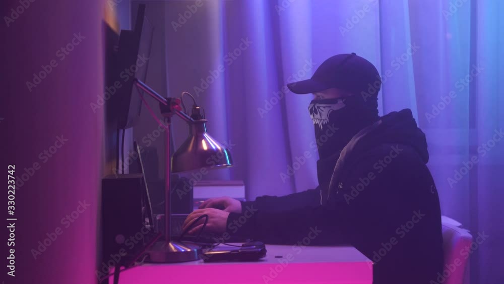Male hacker sits at his desk and breaks into the system. Man in black ...