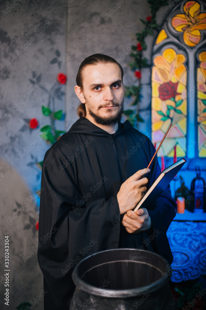 The mage is cooking a potion. A male wizard in a black mantle with a ...