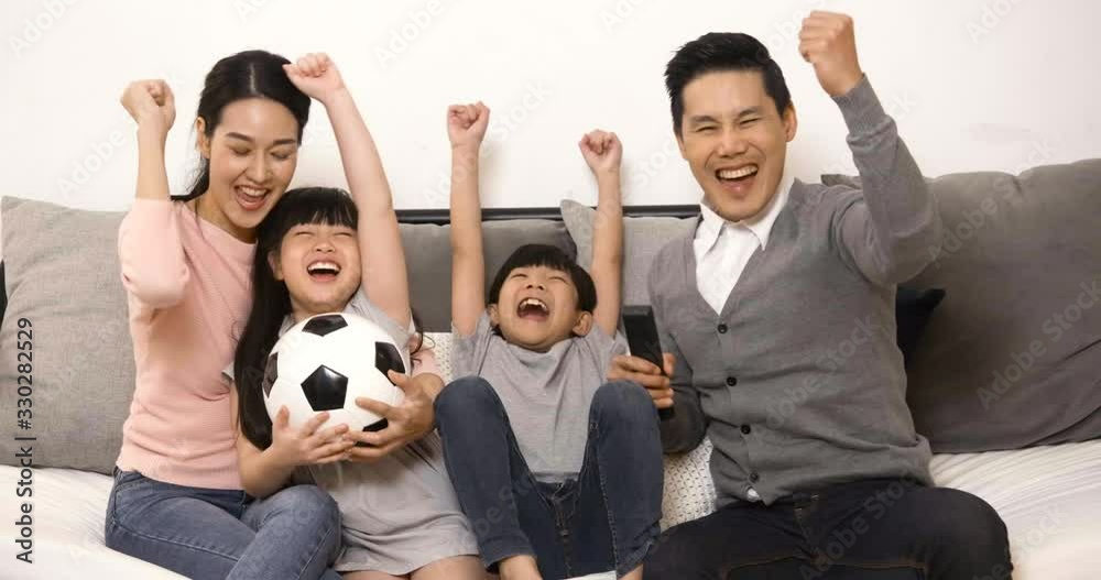 Cheerful young asian parents and cute small kids watching sports ...
