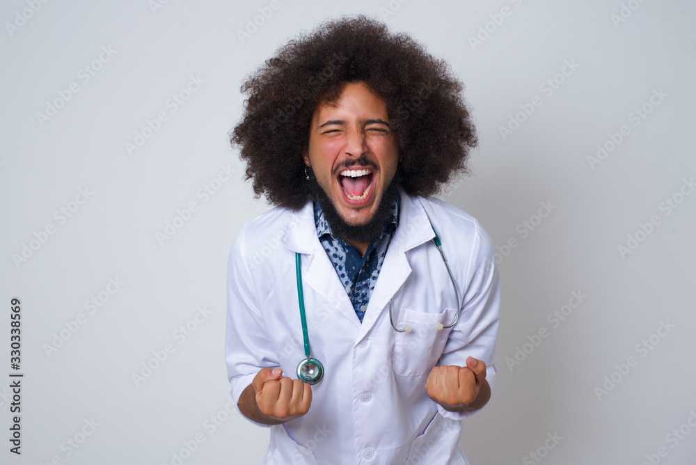 African American doctor man wearing medical uniform raising fists up ...